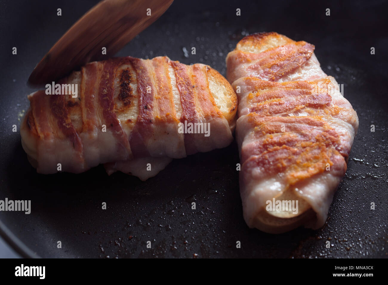 two slices of a loaf wrapped with fried bacon Stock Photo - Alamy