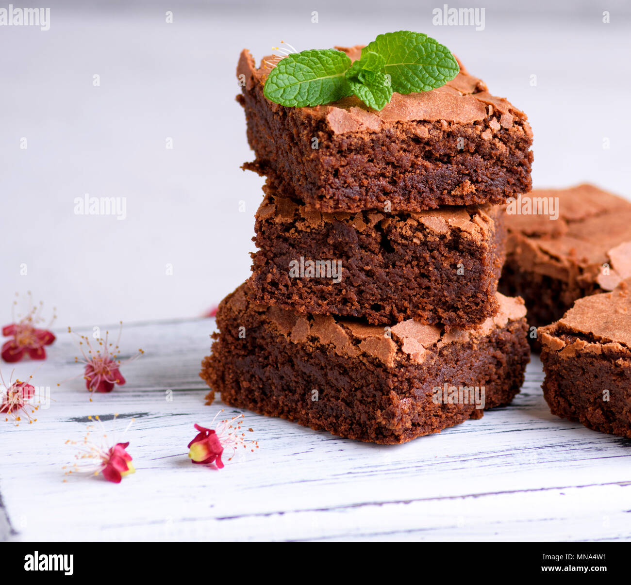 pile of square slices of baked brownie pie on a white wooden board ...