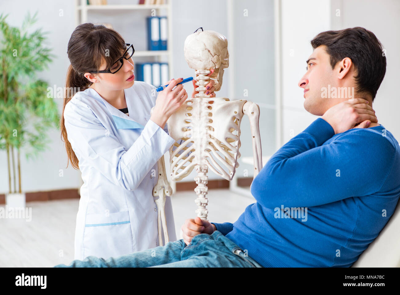 Doctor showing type of injury on skeleton to patient Stock Photo - Alamy