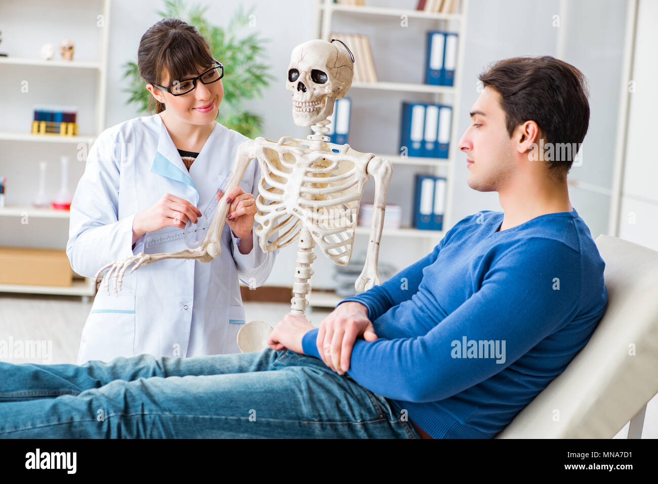 Doctor showing type of injury on skeleton to patient Stock Photo - Alamy
