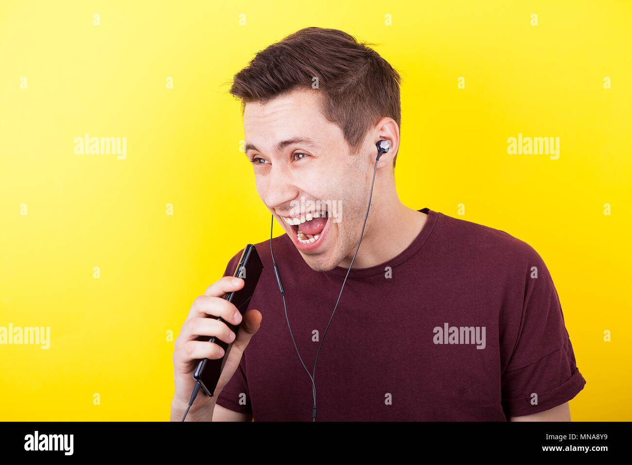 Happy man singing in his phone like a microphone and with headphones in ...
