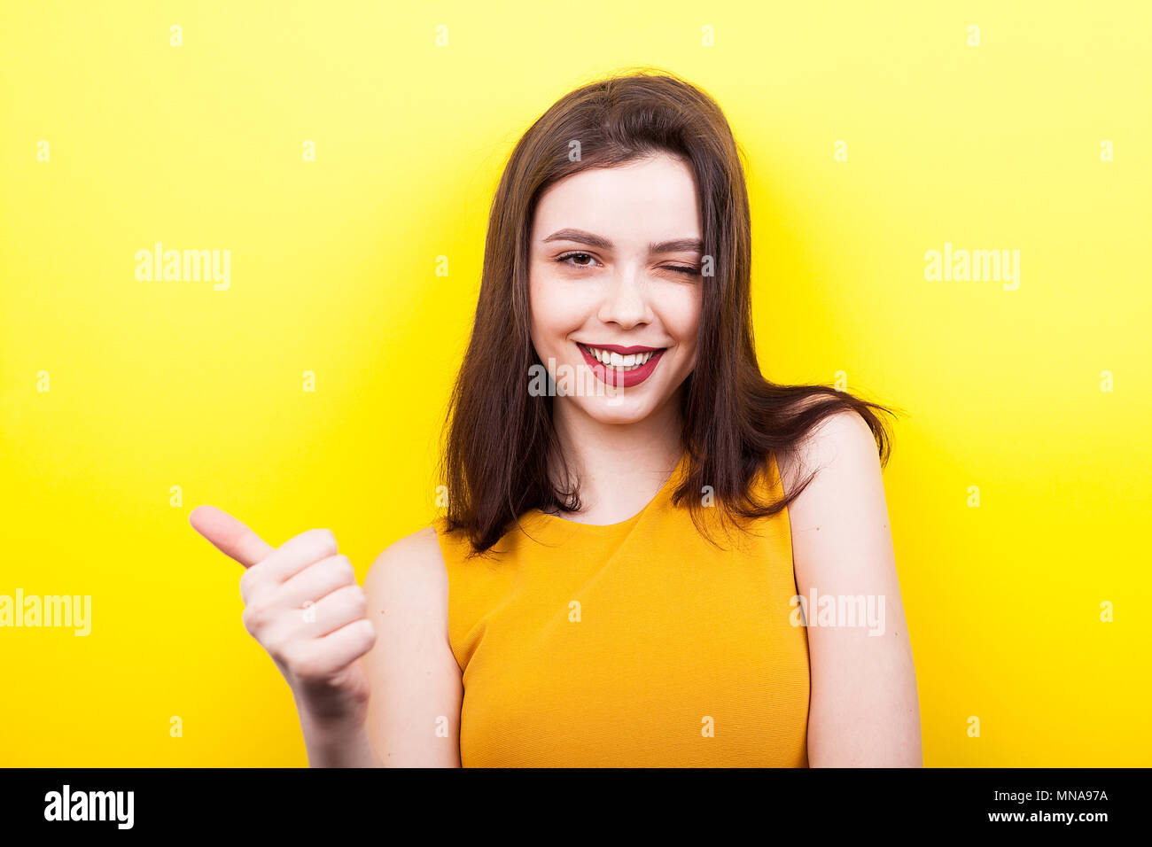 Gorgeous young woman giving a thumbs up and winking Stock Photo - Alamy