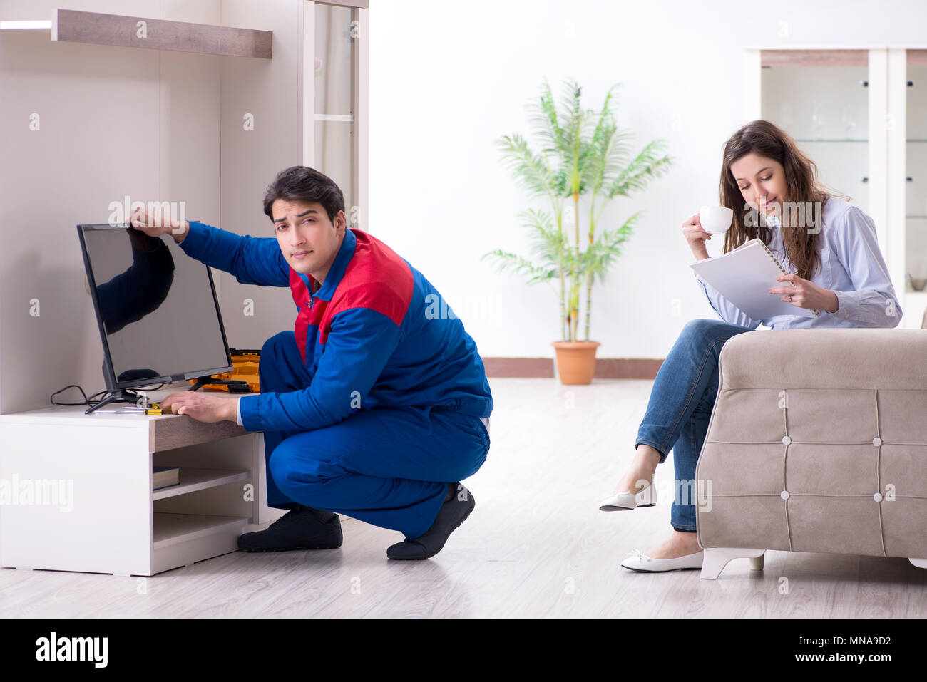 Tv repairman technician repairing tv at home Stock Photo - Alamy