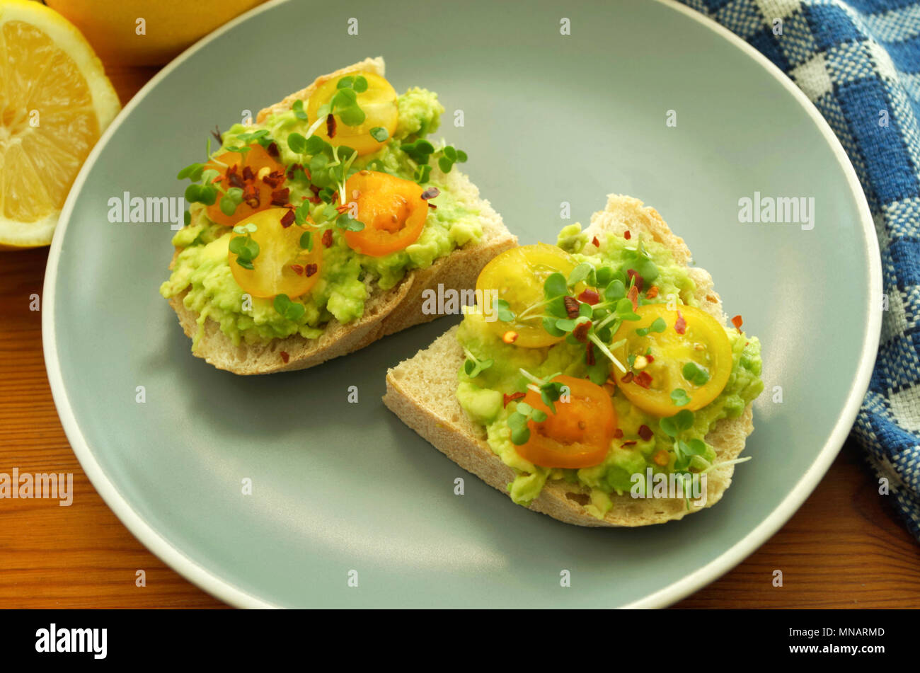avocado on rustic bread with yellow cherry tomatoes, mustard cress and ...