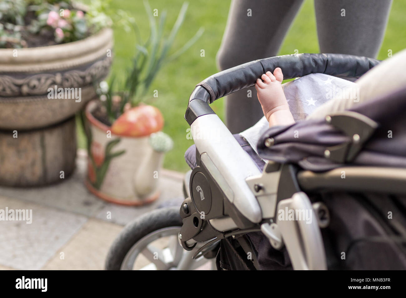 Barefoot kid leg in comfortable stroller.. Child sitting in baby ...