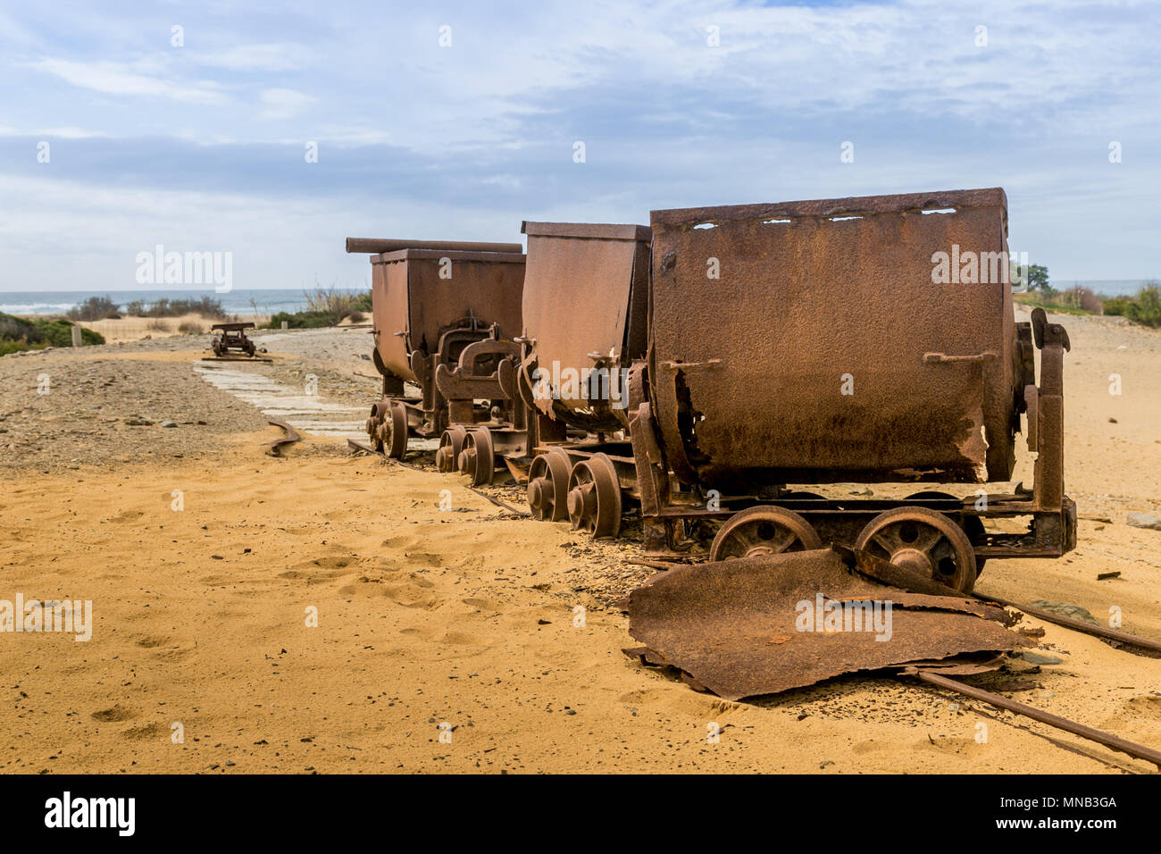 Old and rusty mine carts in the open air on the sand in Sardinia ...
