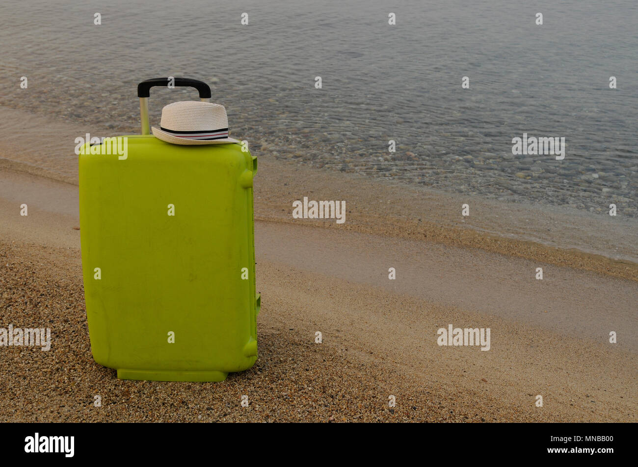 Lemon color suitcase and white hat on the beach Stock Photo - Alamy