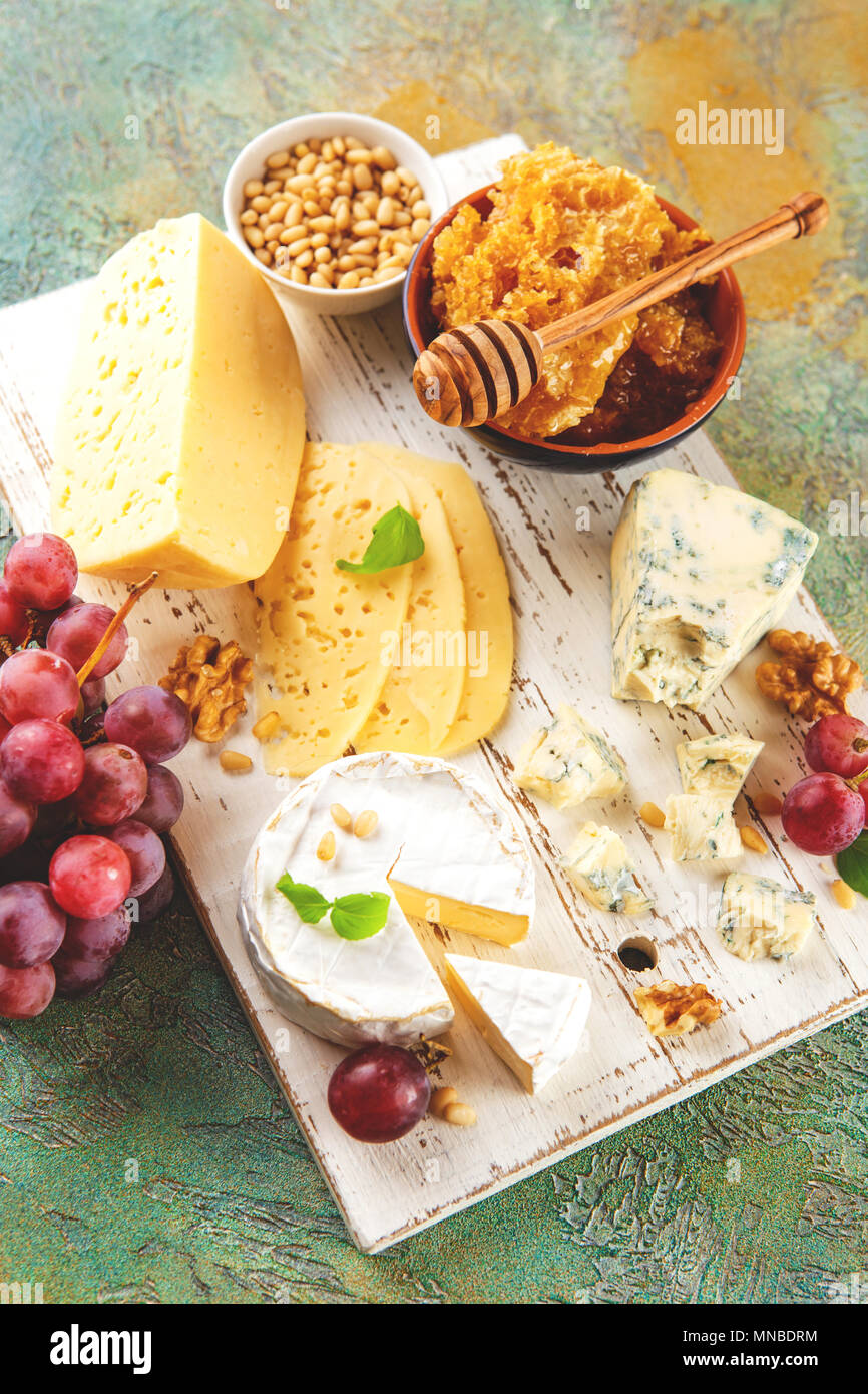 Different types of cheese, red grapes, honeycomb and nuts on a white ...