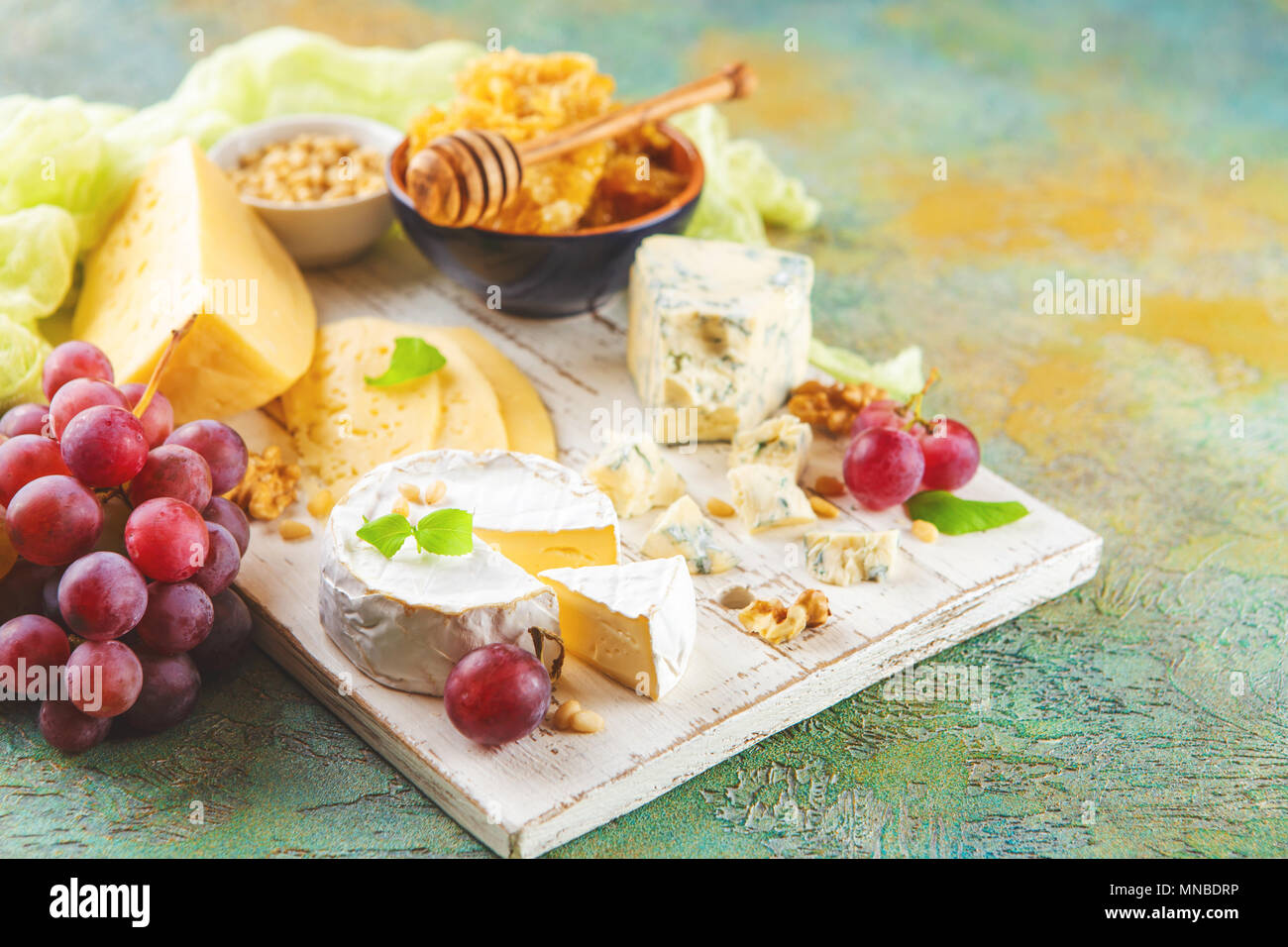 Different types of cheese, red grapes, honeycomb and nuts on a white ...