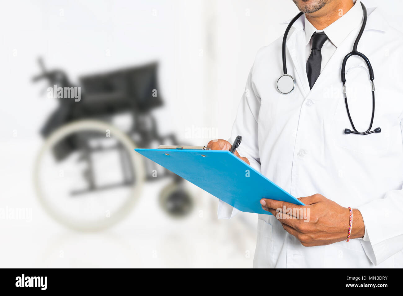 Doctor writing a medical prescription with medical wheelchair in ...