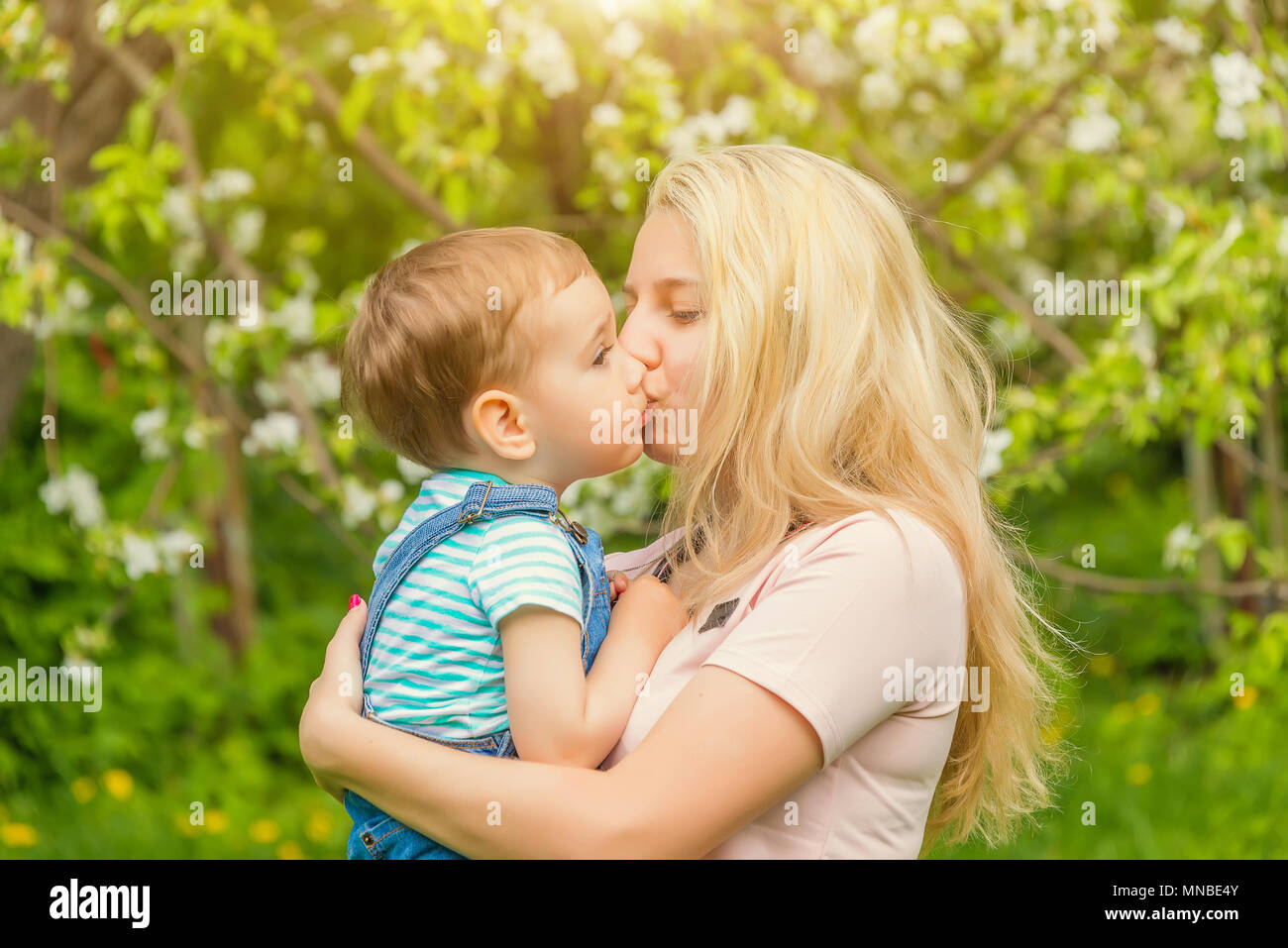 mom hugs and kisses baby in the Park in Sunny weather Stock Photo - Alamy
