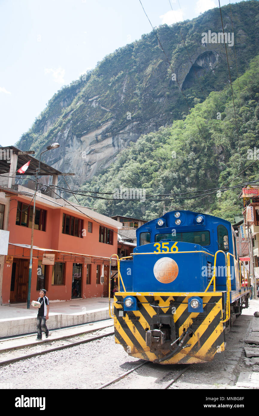 A peru rail train passes by the mountainous town of Aguas Calientes in ...
