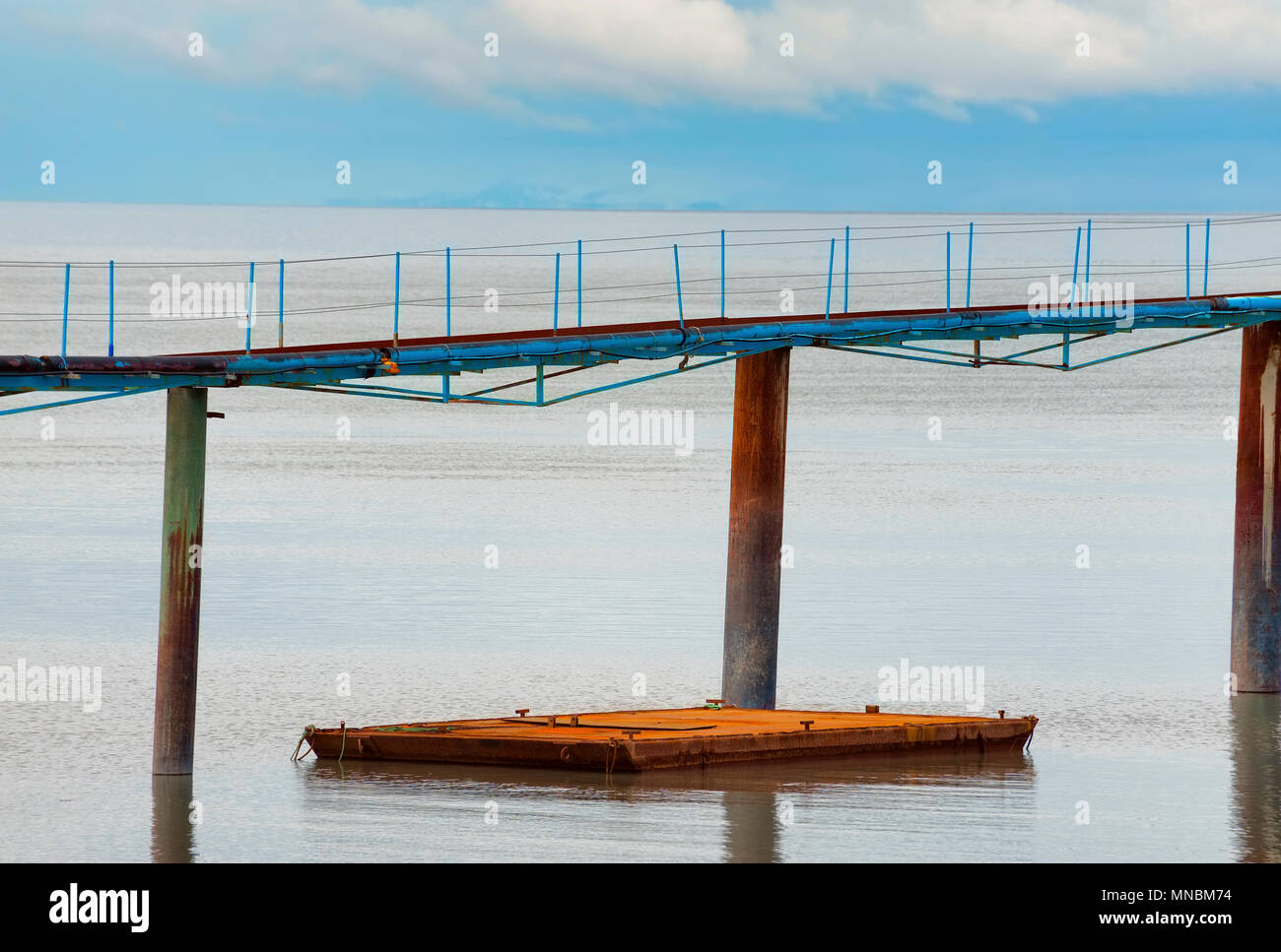 A small dock sits under a piers walkway attached to pilings Stock Photo ...