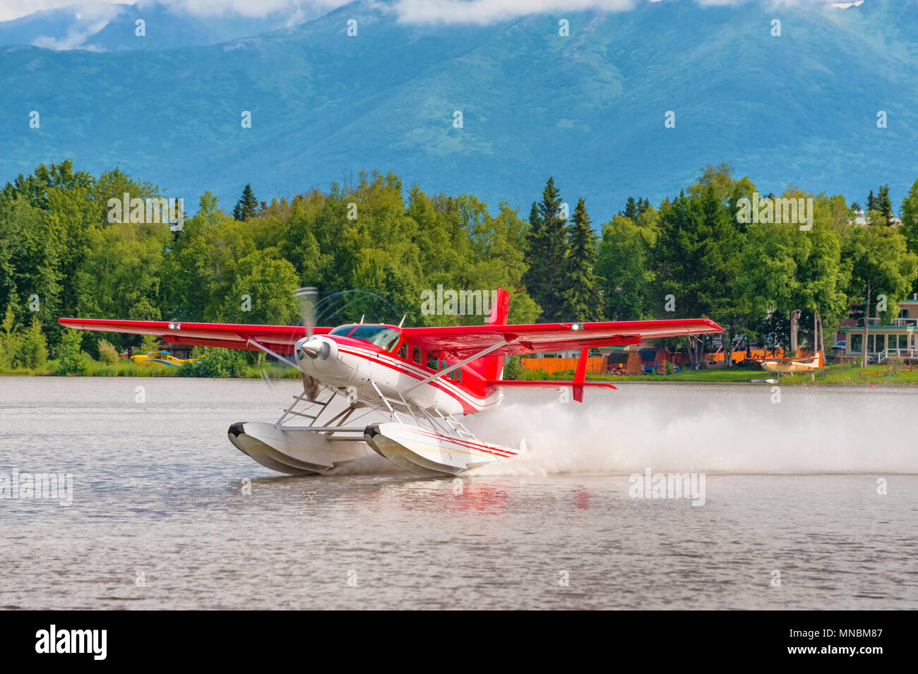 A red and white seaplane takes off on Lake Hood in Anchorage Alaska ...