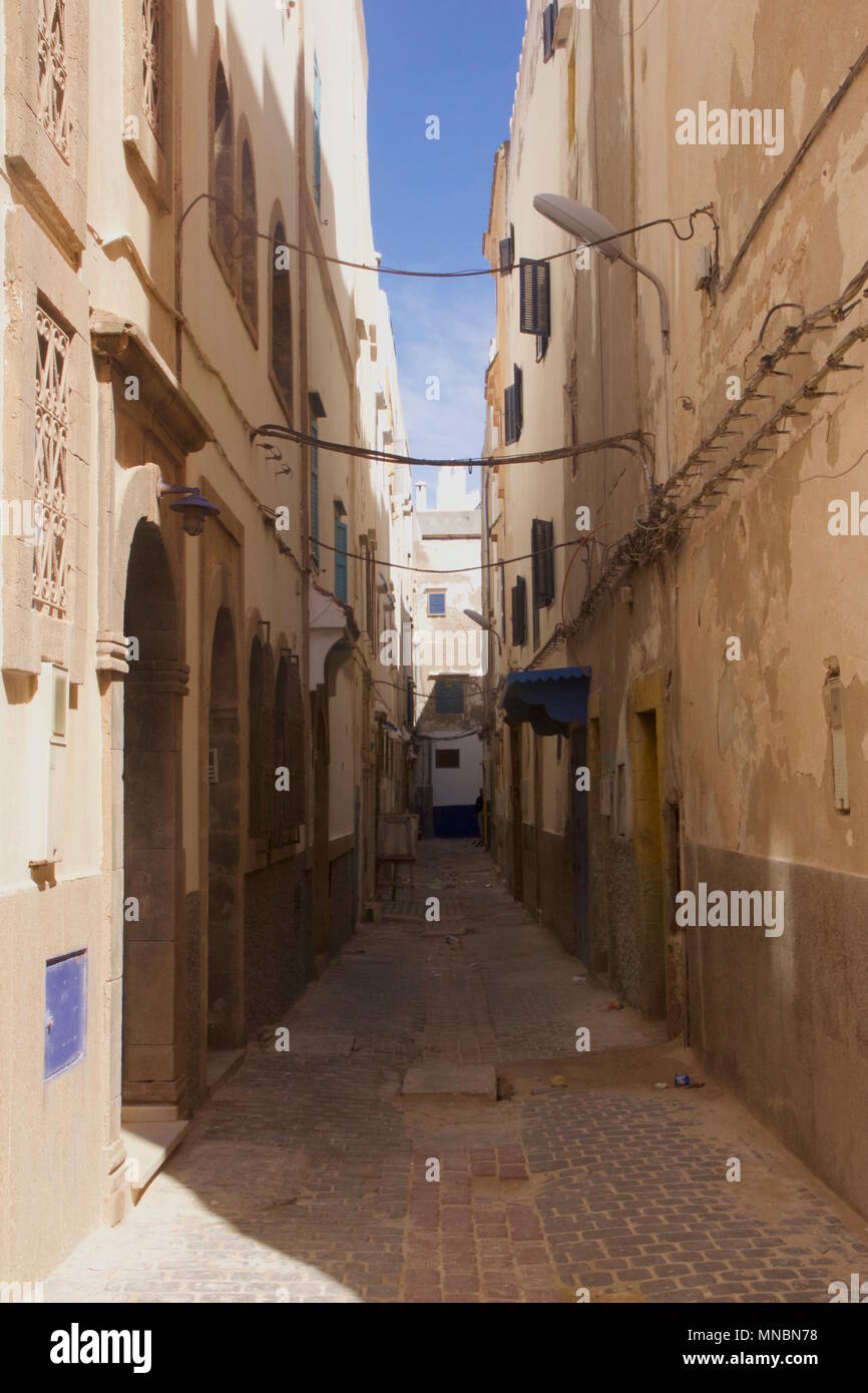 A narrow, tall Moroccan street displaying the architecture in Essaouira ...