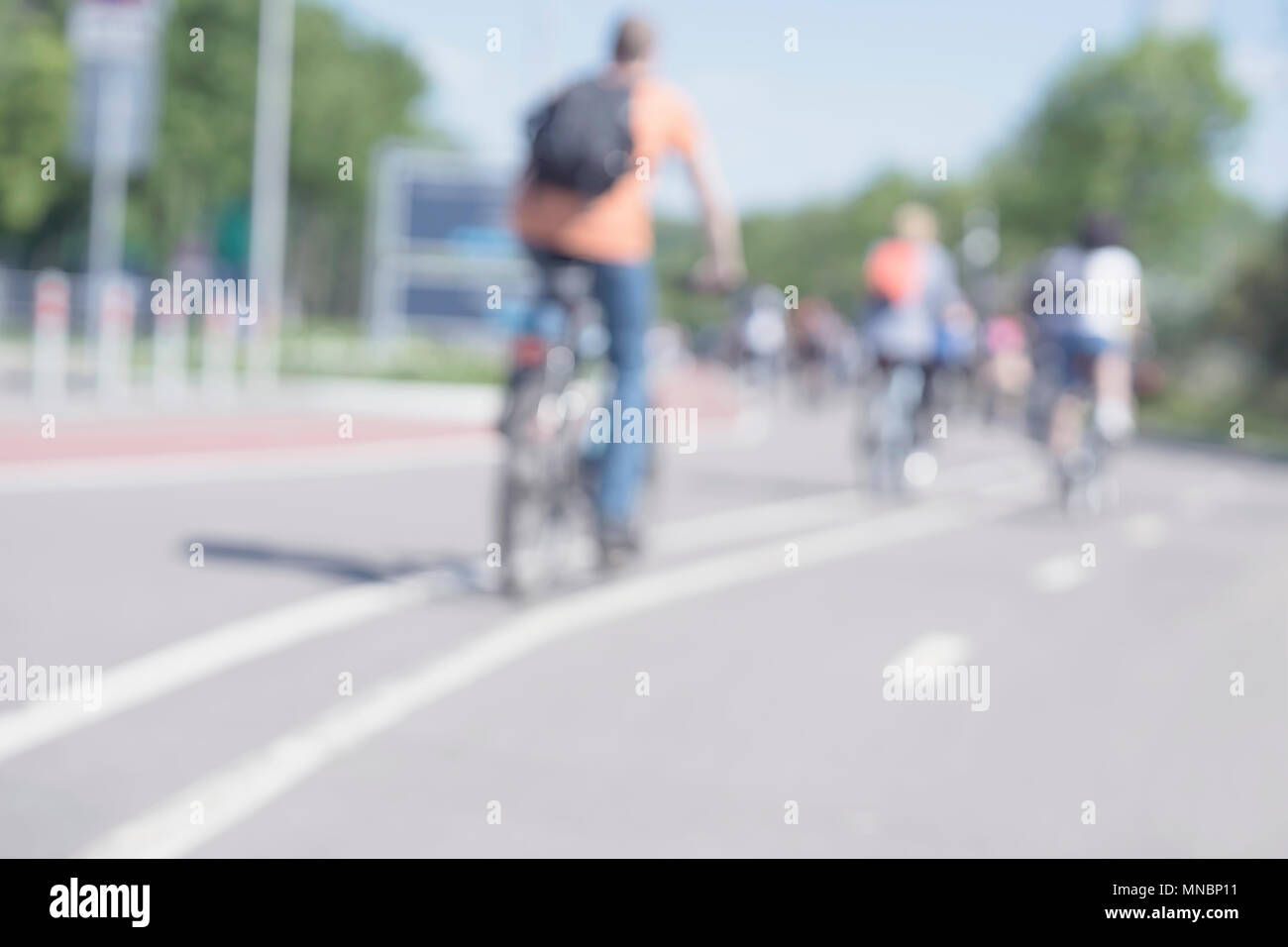 Group of unrecognizable cyclists back to us going outdoor, on the road ...