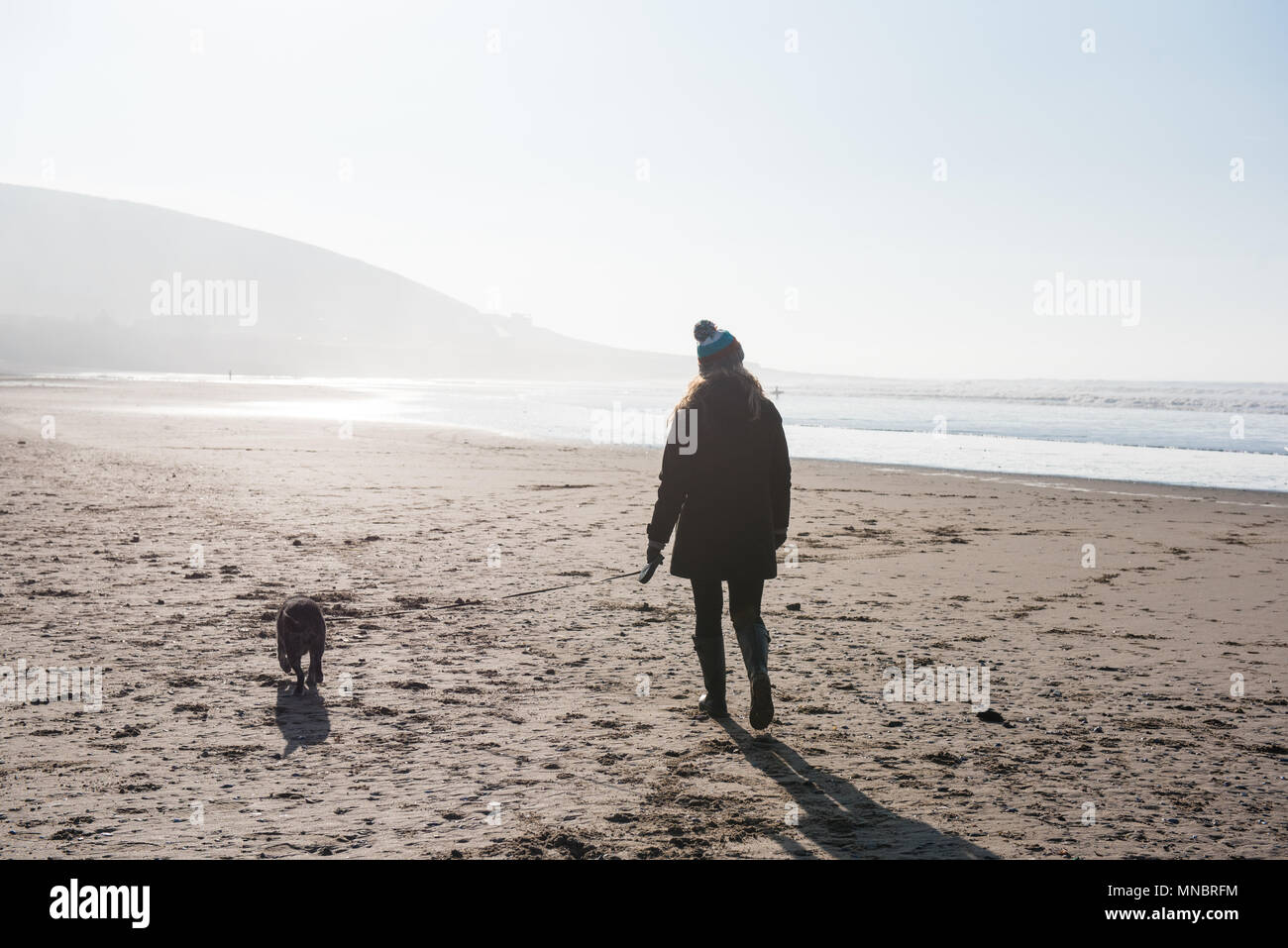 A woman walking her dog on Croyde beach Devon Stock Photo - Alamy