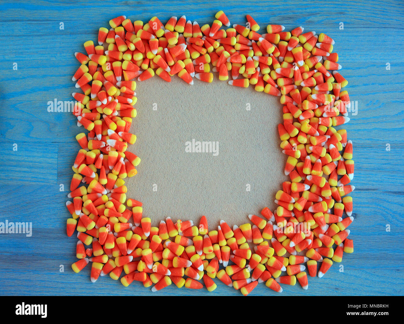 Halloween candy corn inside the shape of a frame. Inside is a beige ...
