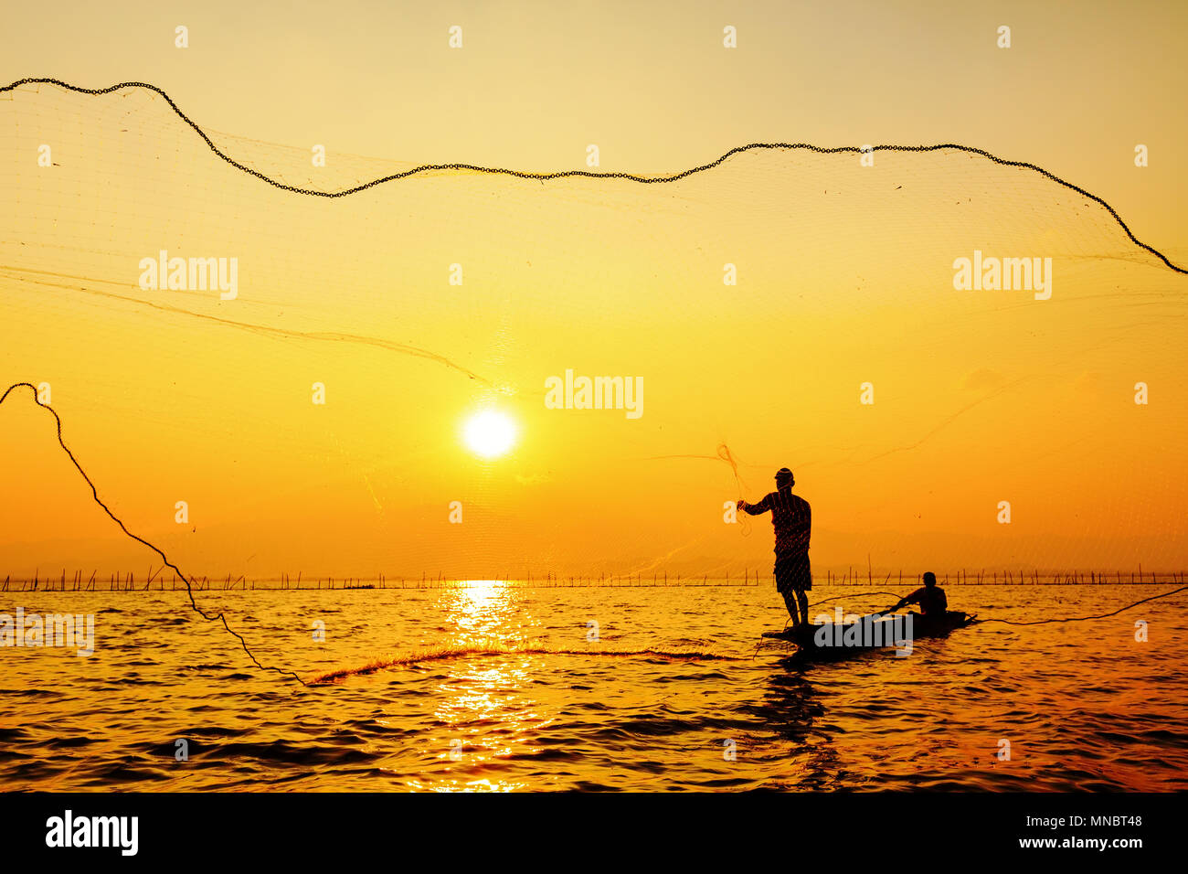Throwing fishing net during sunset Stock Photo - Alamy