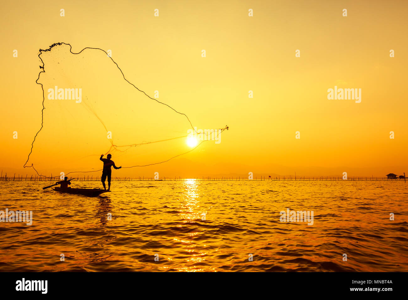 Throwing fishing net during sunset Stock Photo - Alamy