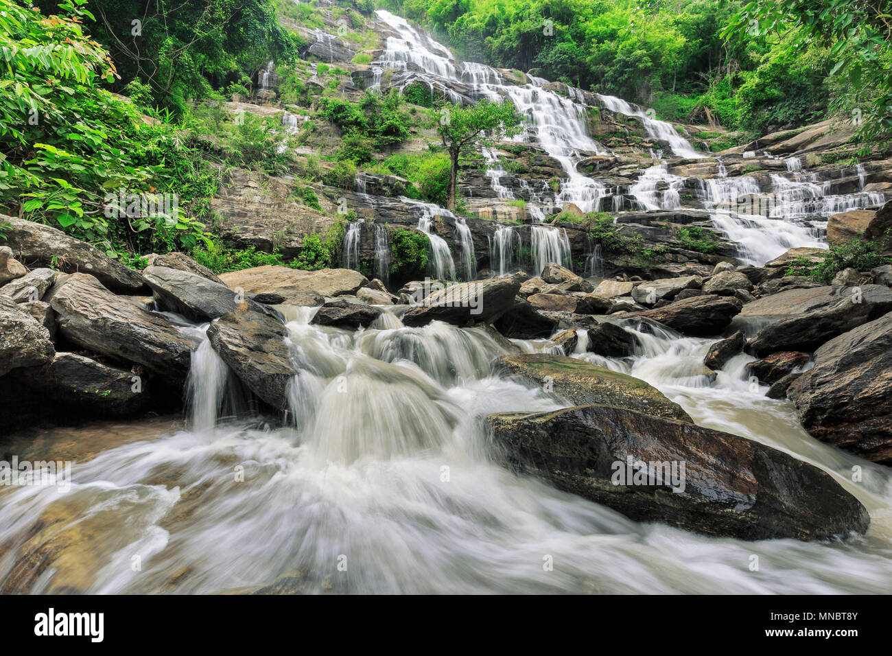 High waterfall filled with rocks and green trees Stock Photo - Alamy