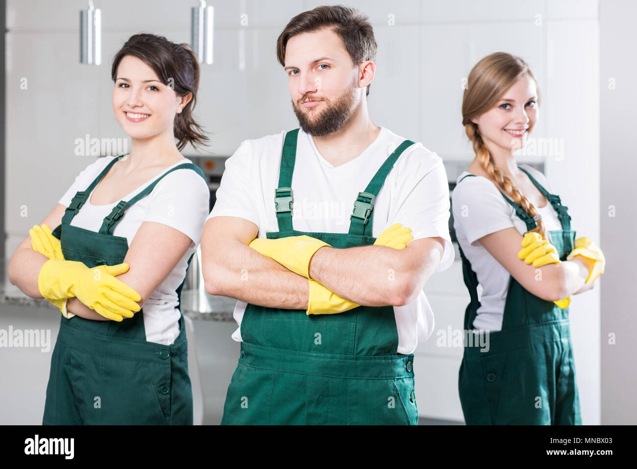Three young people in cleaning uniforms standing together Stock Photo ...