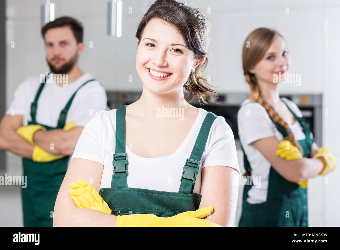 Happy young girl working as a housekeeping. Behind her two colleagues ...