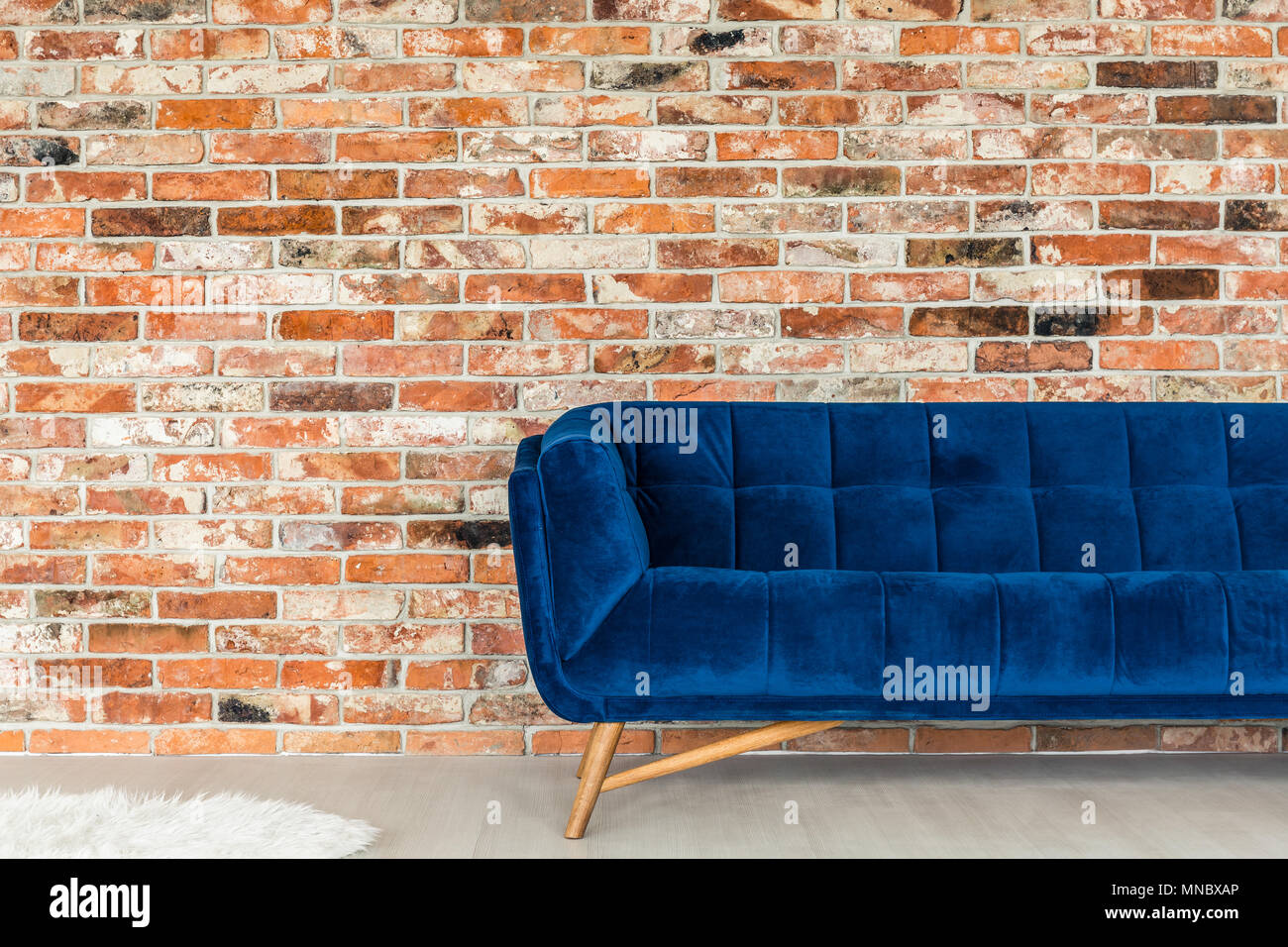 Red brick wall and cobalt blue upholstered sofa Stock Photo - Alamy
