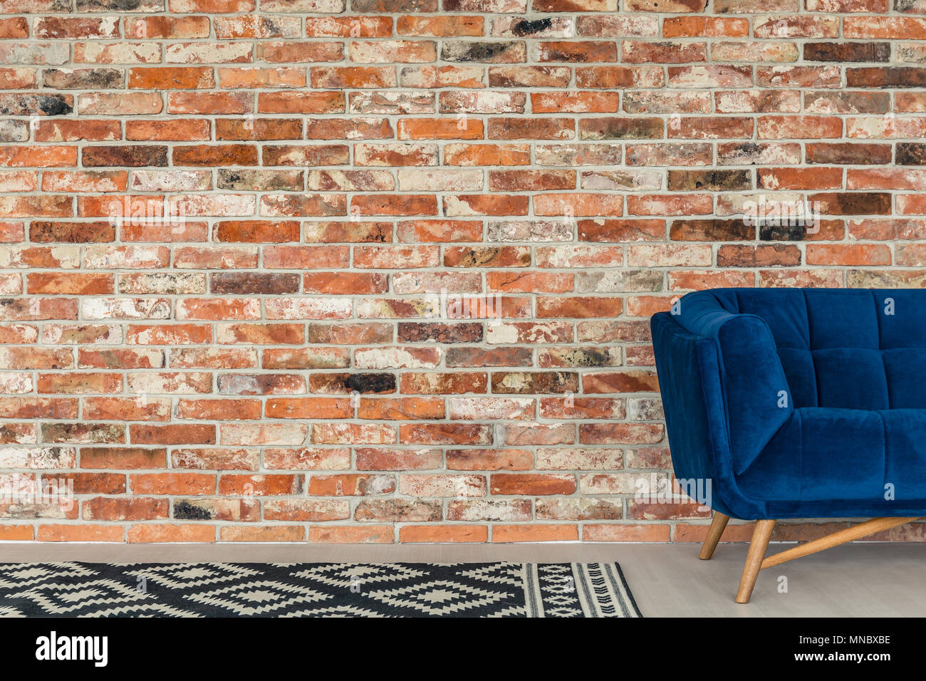 Red brick wall, blue sofa and pattern rug Stock Photo - Alamy