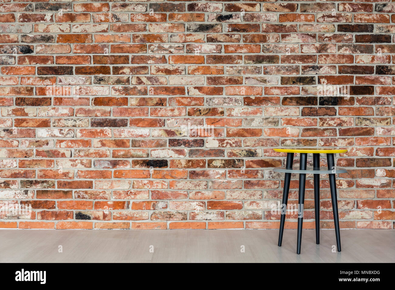 Modern side table and red brick wall Stock Photo - Alamy