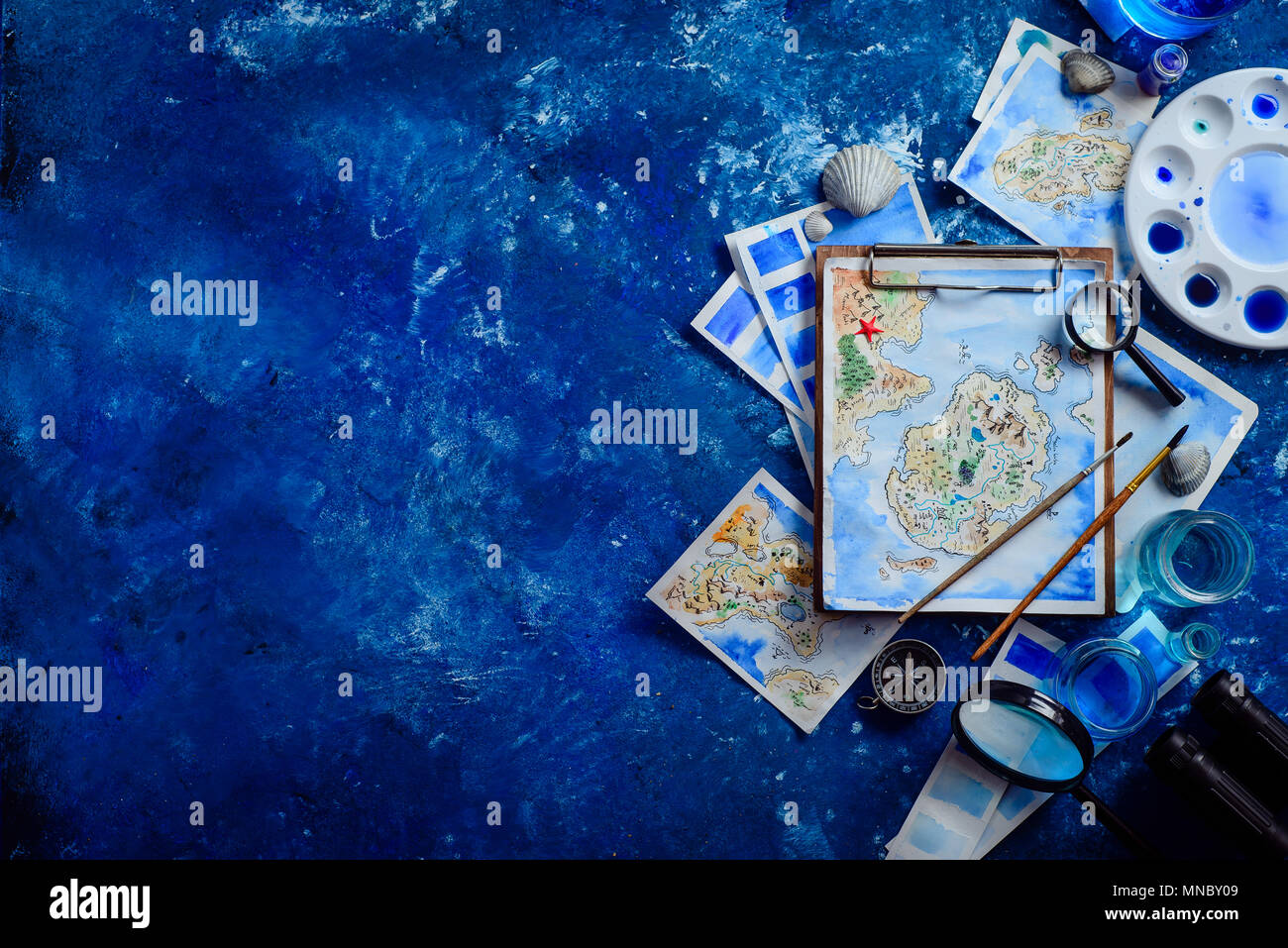 Fantasy maps on a wooden clipboard in an artist workplace with sketches ...