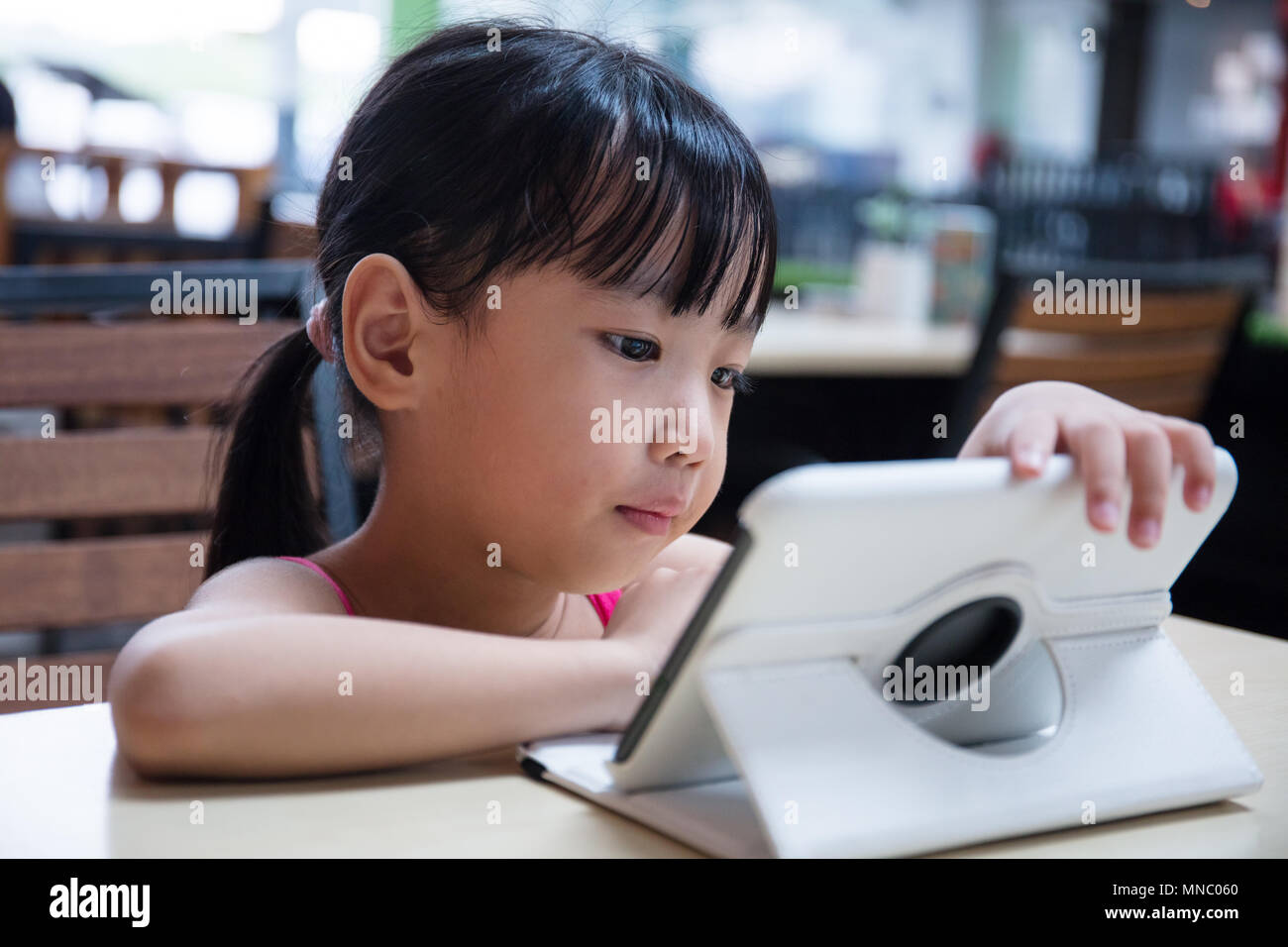 Asian Chinese little girl playing tablet computer at outdoor cafe Stock ...