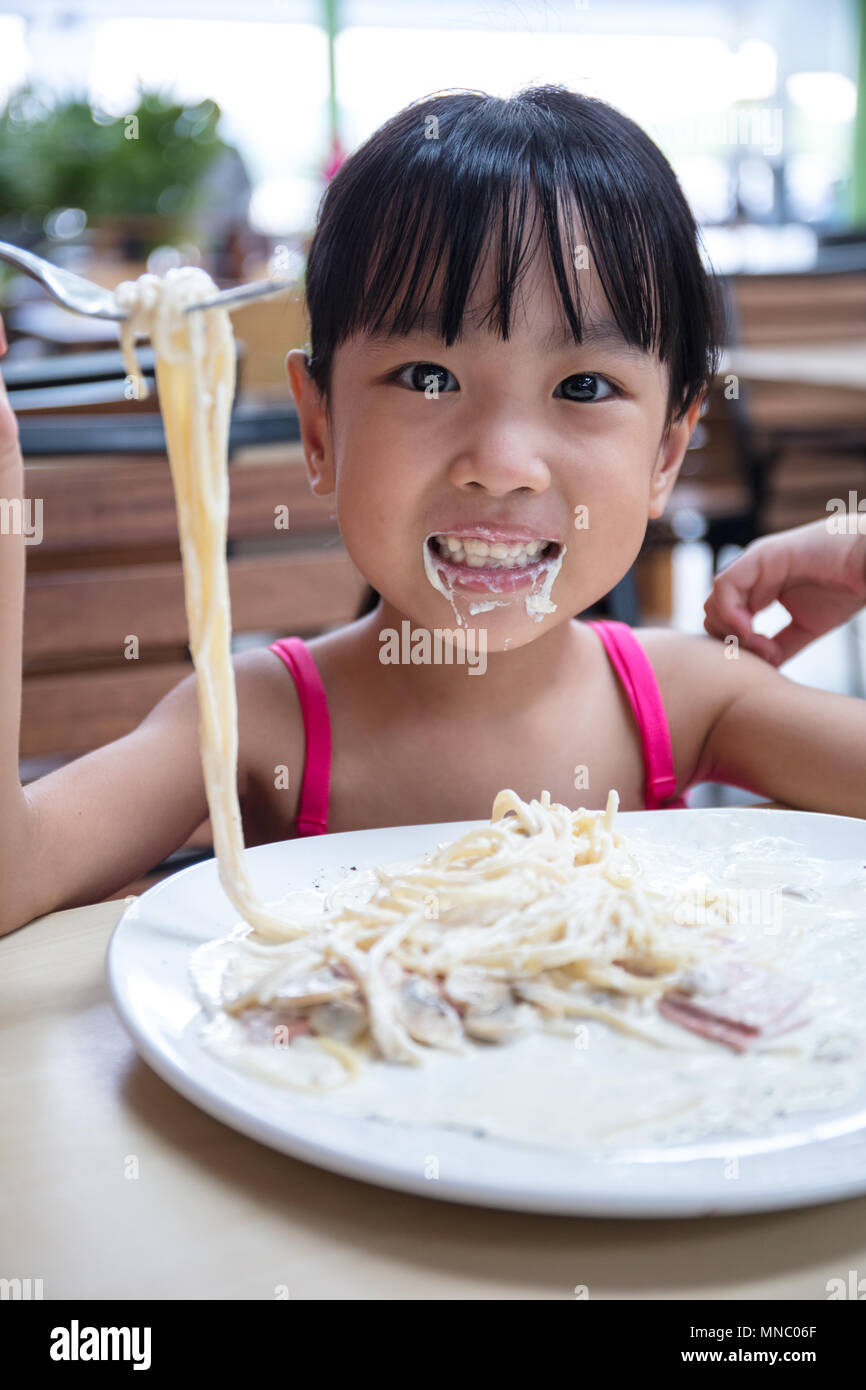 Asian Chinese little girl eating spaghetti at outdoor cafe Stock Photo ...