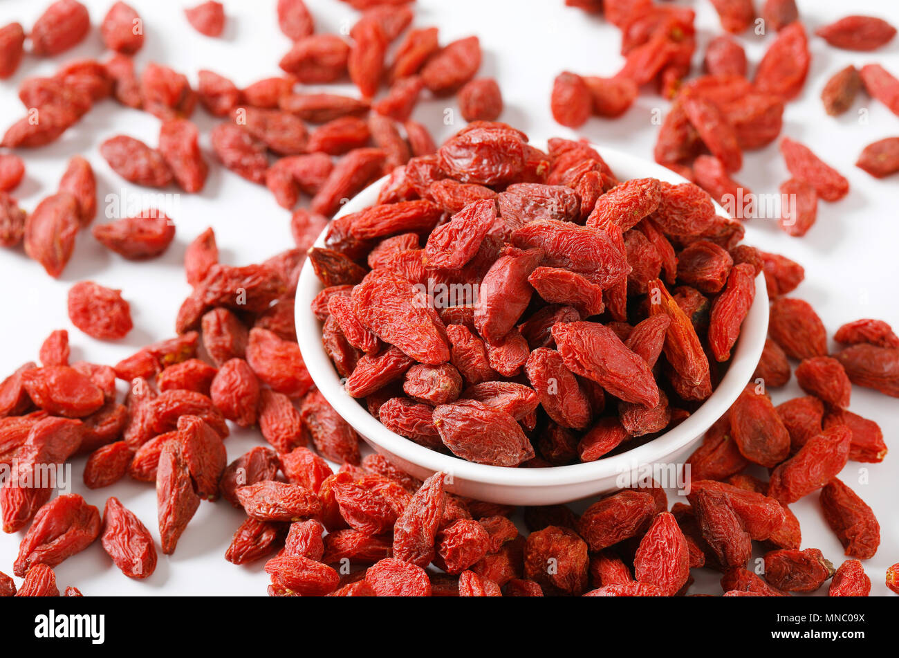 bowl and pile of healthy goji berries on white background Stock Photo ...