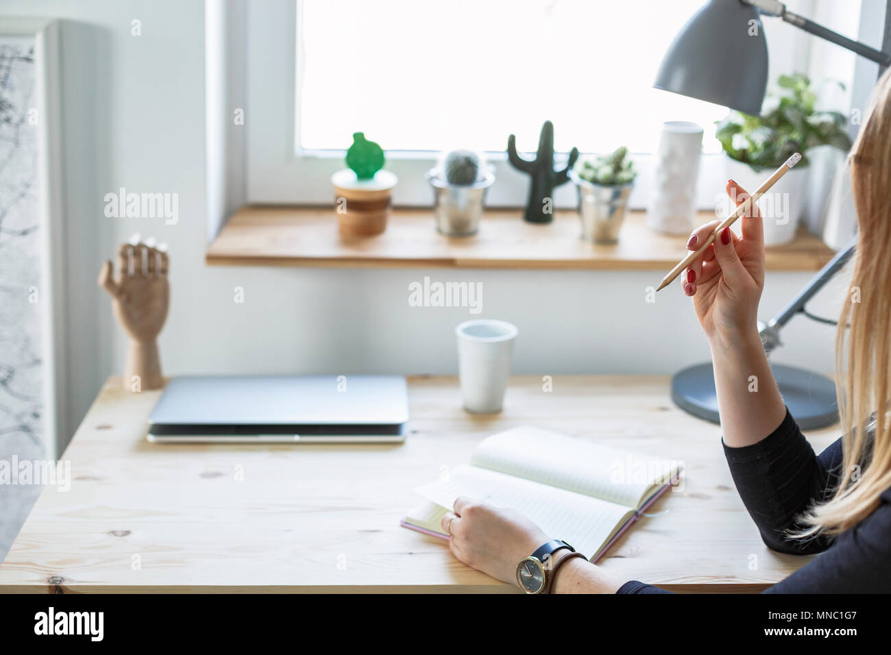 Freelancer woman with pencil taking notes while working in home office ...