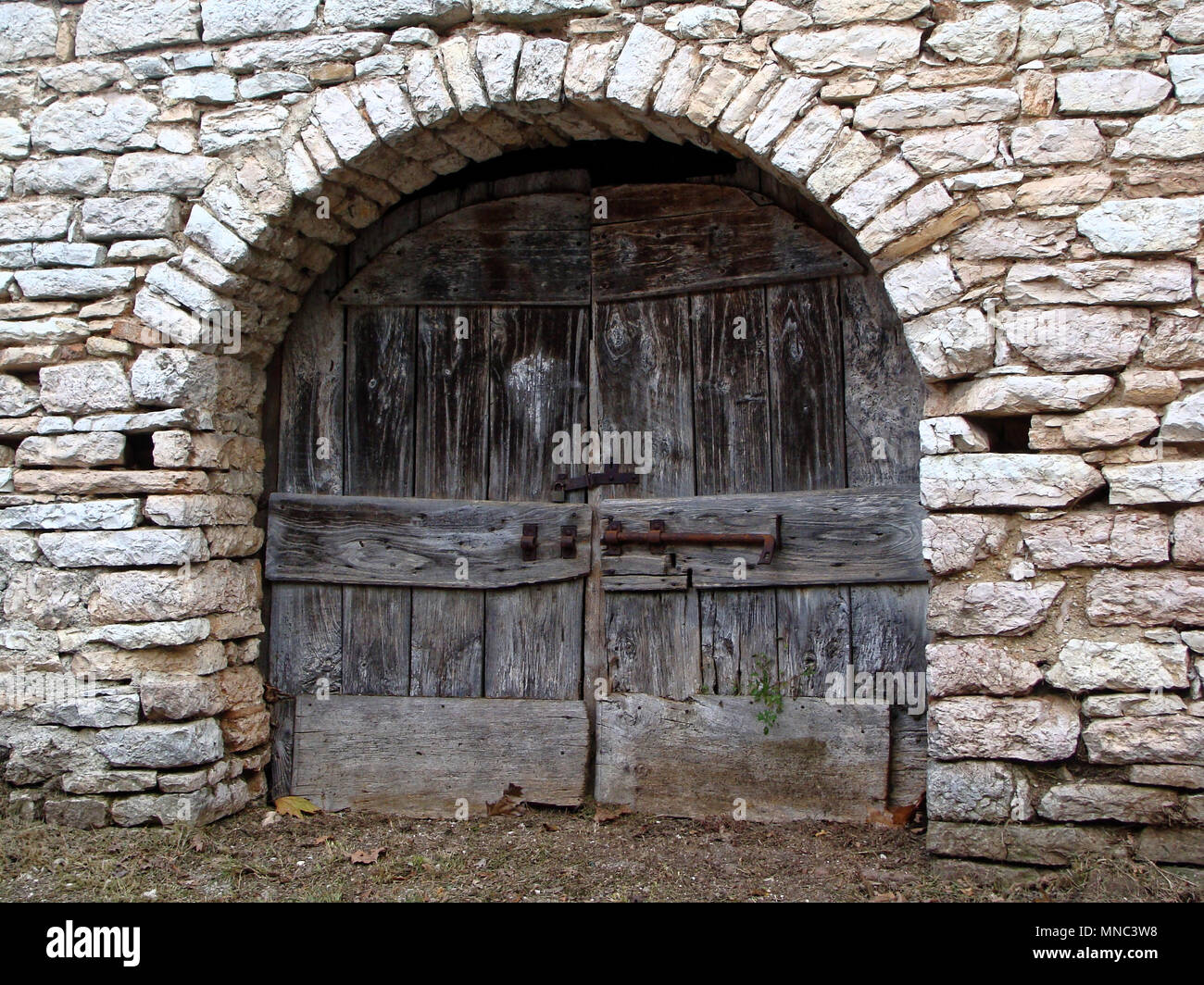 Old antique wooden door or gate. The door in the stone wall cracked ...