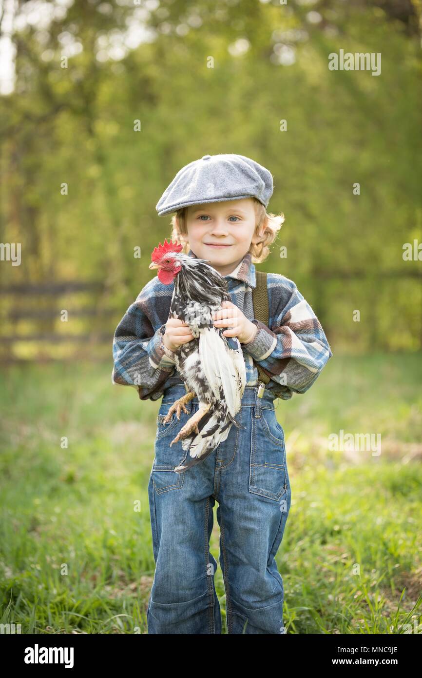 Small boy portrait with chicken. Caucasian curly haired boy in hat ...