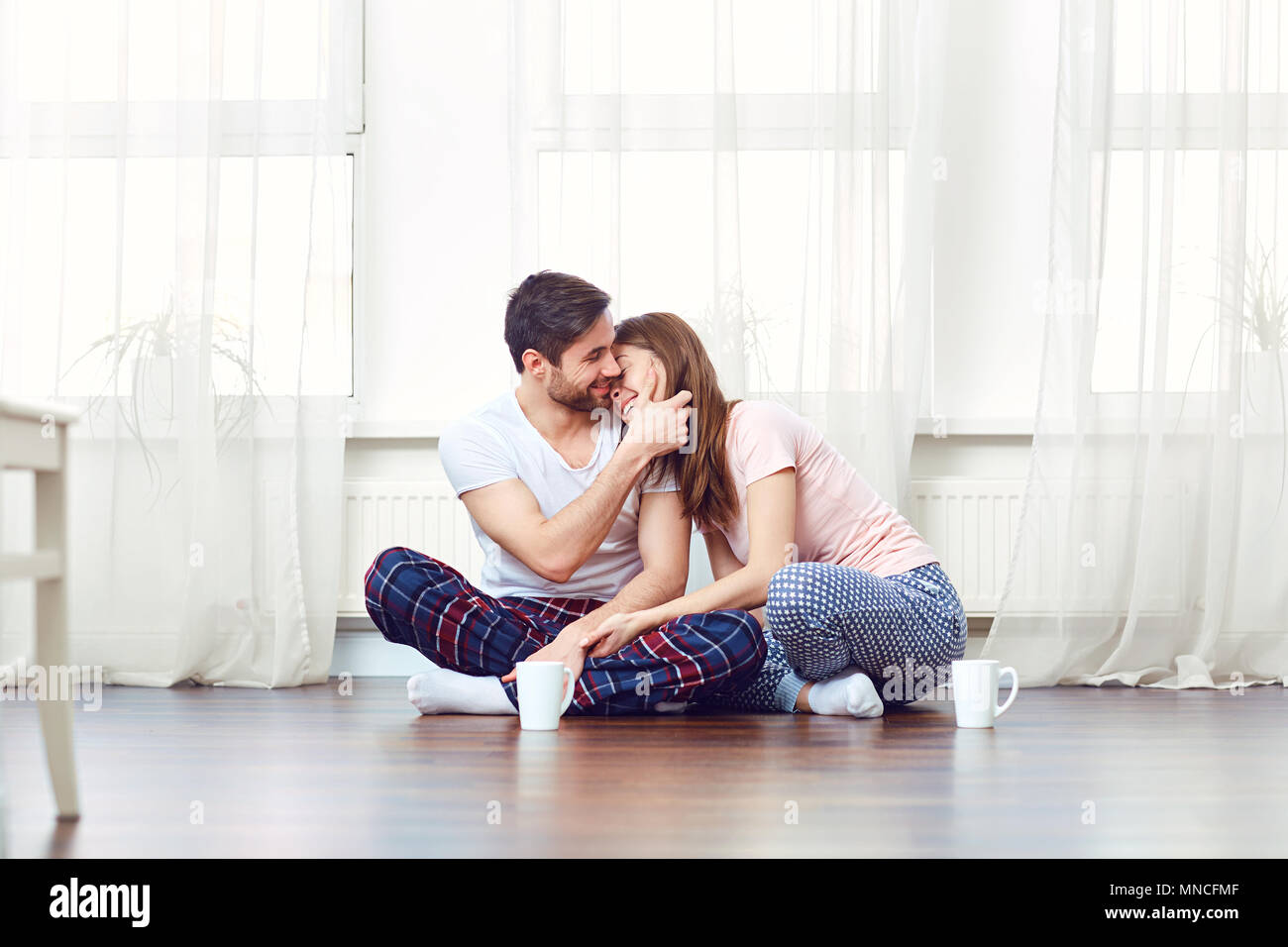 A loving couple hugging on the floor against the window Stock Photo - Alamy
