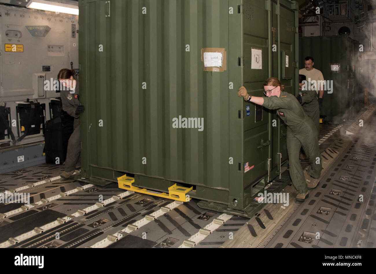 Airman assigned to the 21st Airlift Squadron, push a cargo pallet into ...