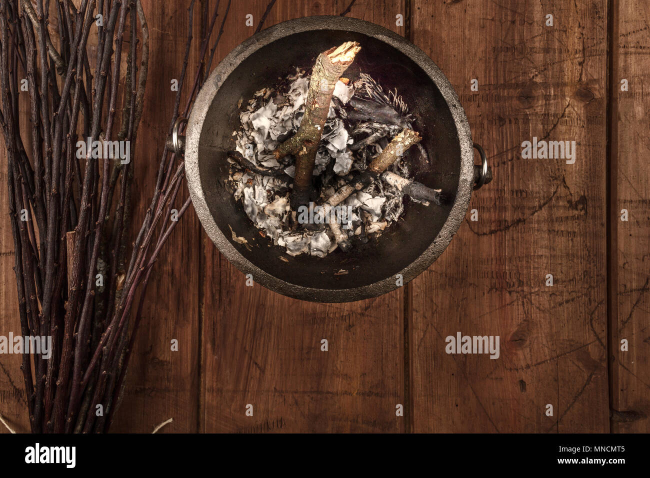 An overhead photo of a witch's cauldron with ashes and wooden sticks ...
