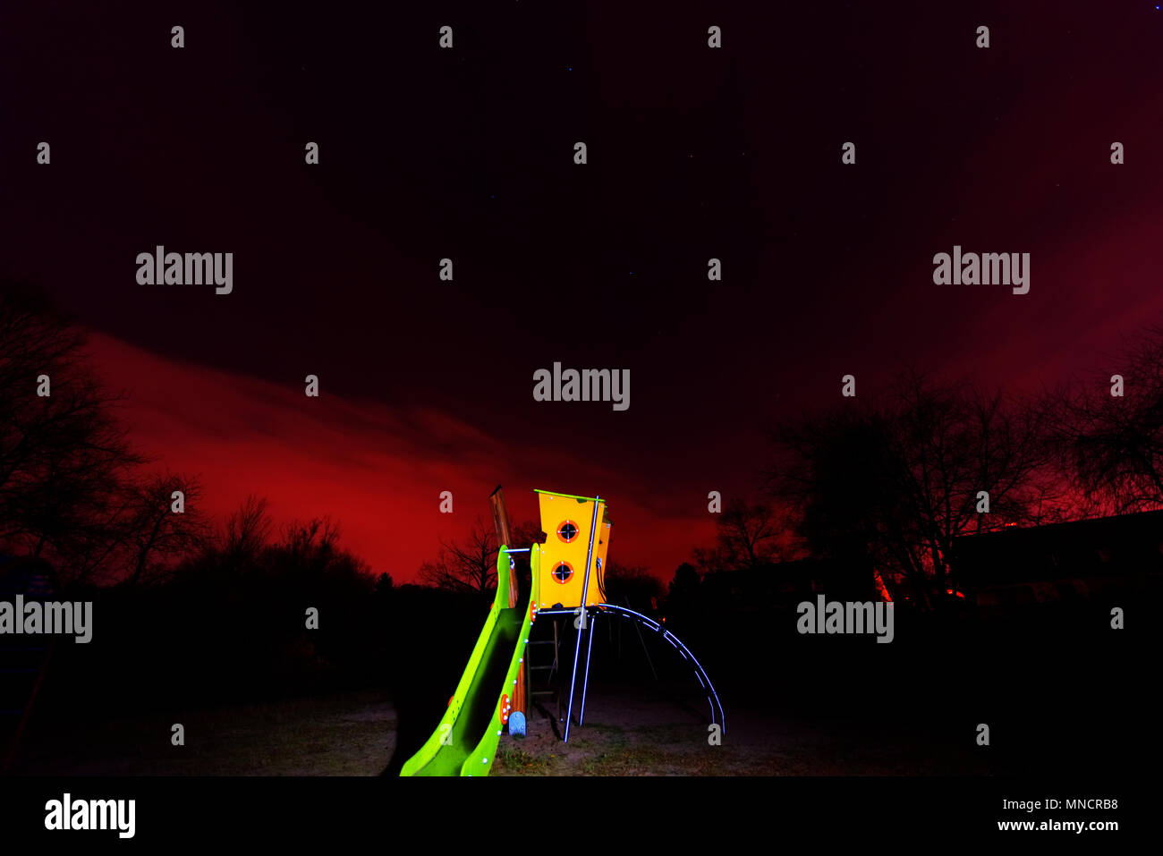 playground at night unter red sky wallpaper background Stock Photo - Alamy