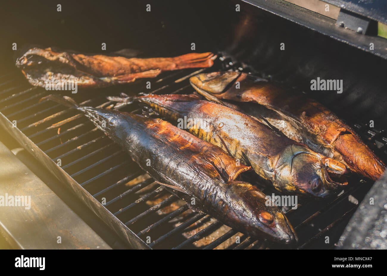 Smoked fish in smokehouse. Three sardines and sea bass Stock Photo - Alamy
