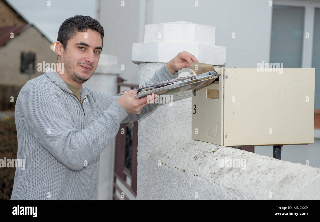 young man putting newspaper from the mailbox Stock Photo - Alamy