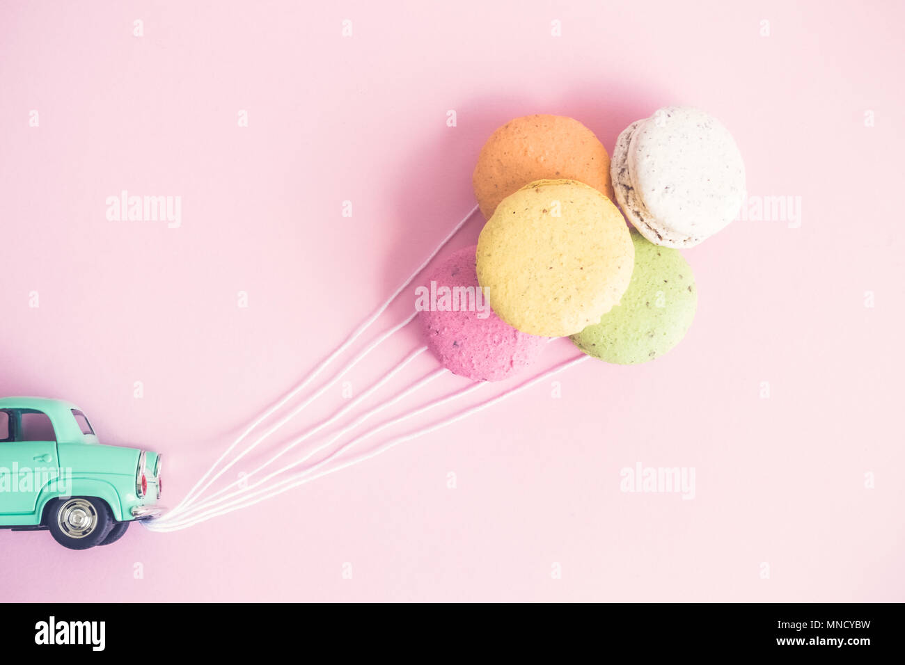 Flat lay of car model with colorful macaroons in form of balloons. Just ...
