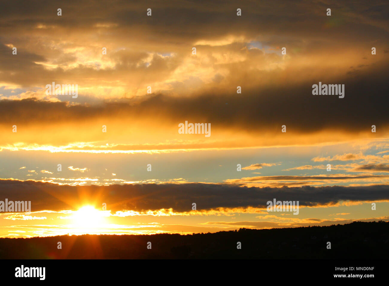 Sunset time above a small lake. The clouds. are standing in a ...