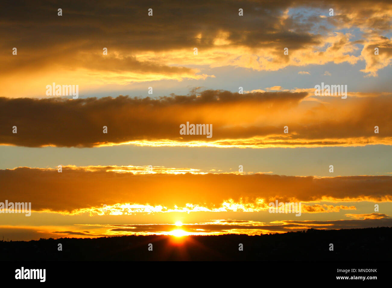 Sunset time above a small lake. The clouds. are standing in a ...