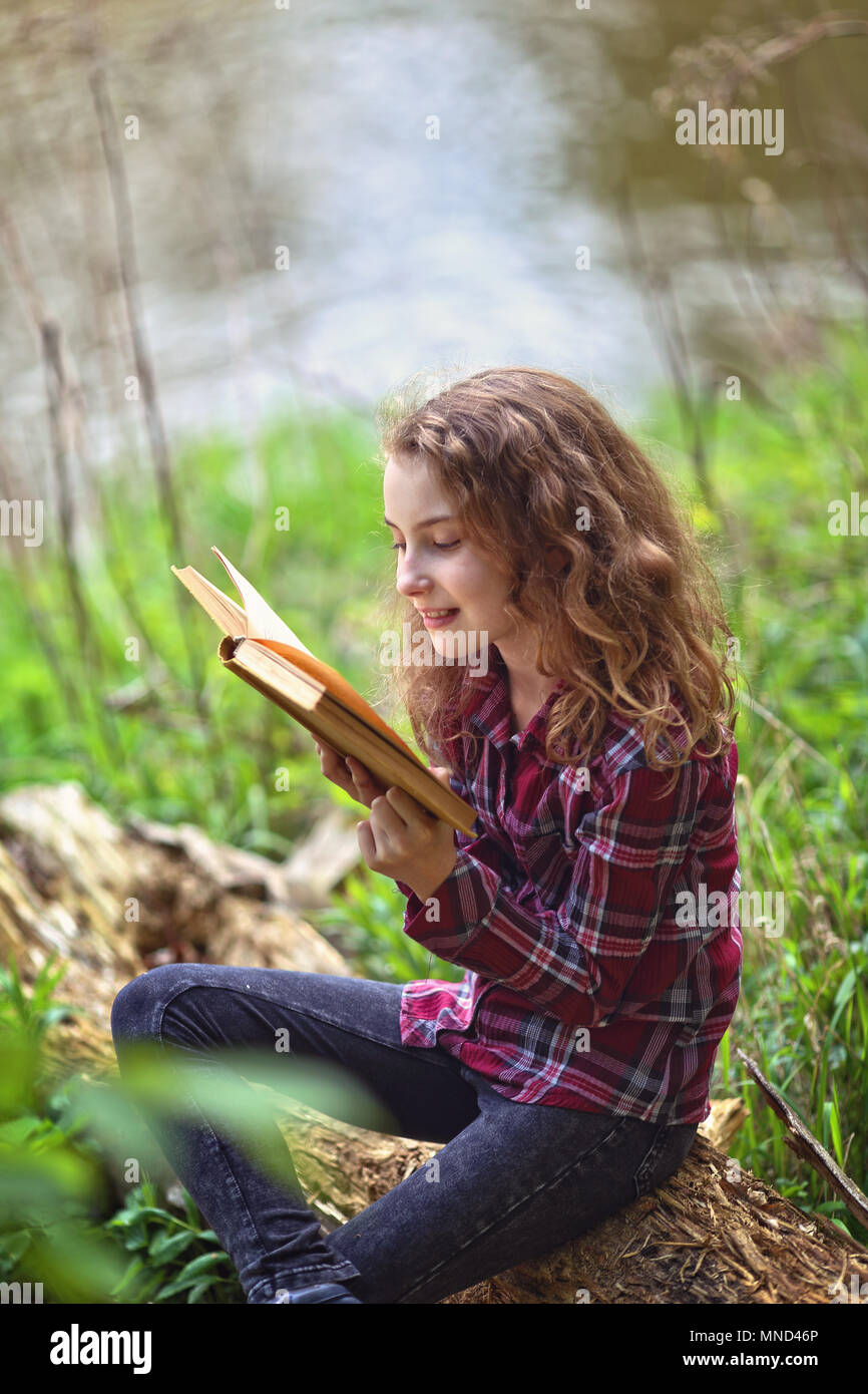 Joyful girl is reading a book in nature Stock Photo - Alamy