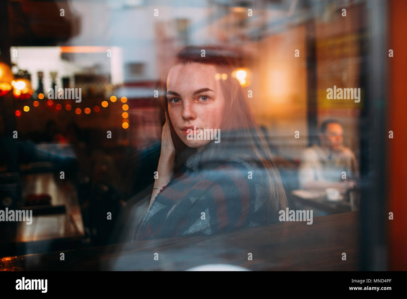 Beautiful young woman seen through cafe window Stock Photo - Alamy