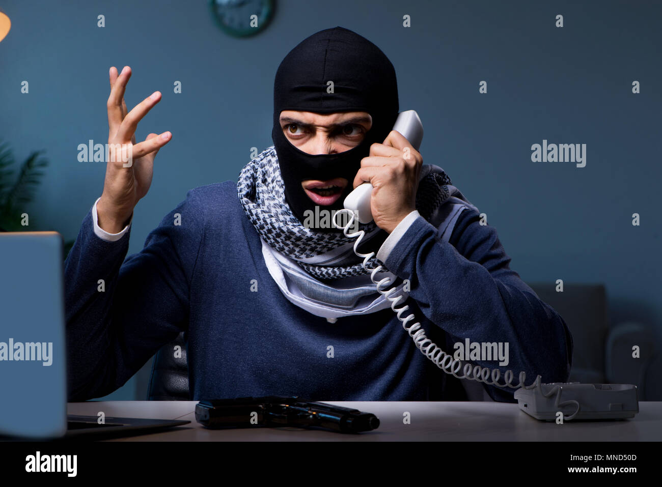 Terrorist burglar with gun working at computer Stock Photo - Alamy