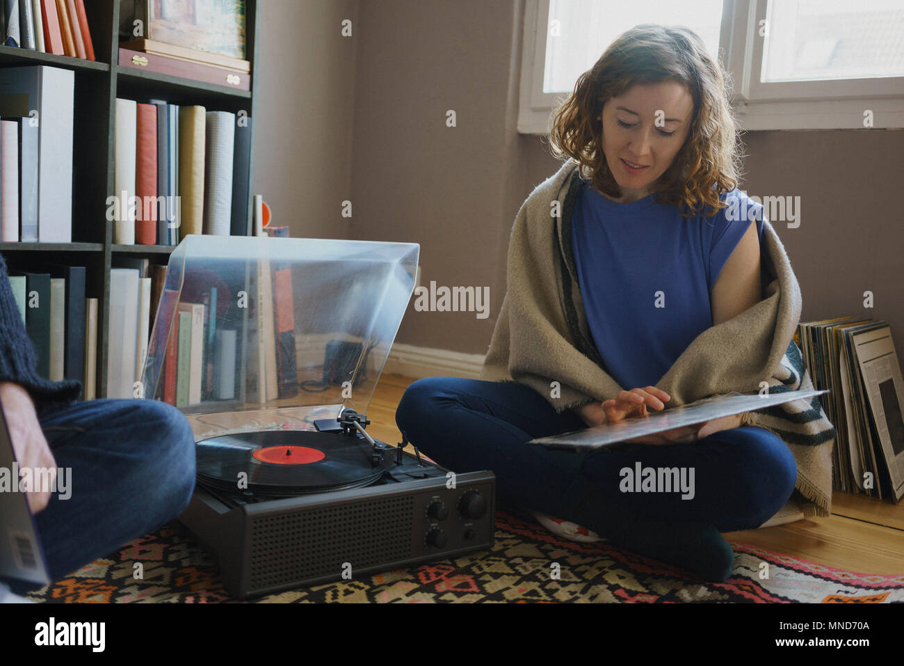 Woman sitting with record by turntable and man on carpet at home Stock ...